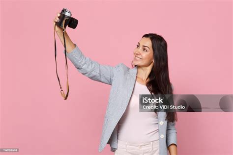 분홍색 파스텔 벽 배경에 고립 된 복고풍 빈티지 사진 카메라에 Selfie 샷을 하 고 줄무늬 재킷에 웃는 젊은 여자의 초상화 사람들은 진지한 감정 라이프 스타일 개념입니다
