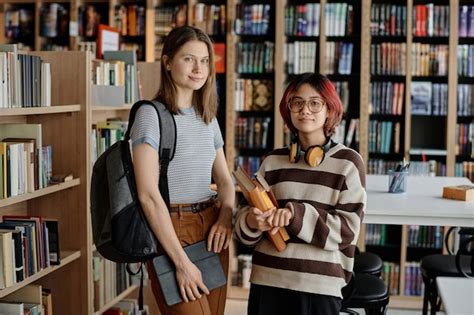 Two Girls Standing In Library Premium Photo