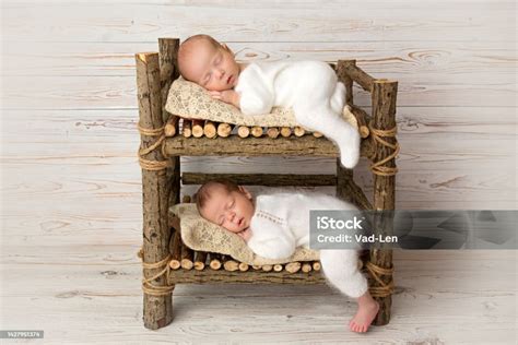 밝은 나무 배경에 흰색 보디 슈트를 입은 작은 신생아 쌍둥이 소년 신생아 쌍둥이는 이층 나무 침대에서 자고 있습니다 소년들 전문