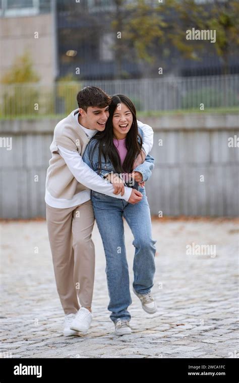 A Young Couple Laughing And Hugging While Walking Along A Cobblestone