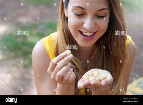 Beautiful Girl Eating Macadamia Nuts Outdoor Looks At Macadamia Nuts