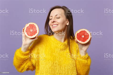 모피 스웨터에 예쁜 젊은 여 자가 보라색 파스텔 배경에 고립 된 신선한 잘 익은 자 몽의 Halfs 지주를 유지 사람들은 생생한 라이프 스타일 휴식 휴가 개념입니다 복사