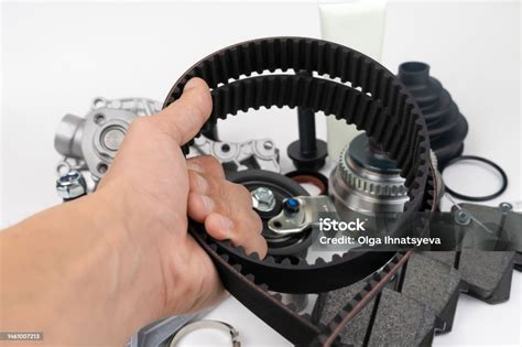자동차 엔진의 가스 분배 시스템의 타이밍 벨트 및 텐션 롤러 자동차 유지 보수의 개념 마스터의 손은 흰색 배경에 예비 부품의 배경에 타이밍 벨트를 잡고 있습니다 강철에 대한