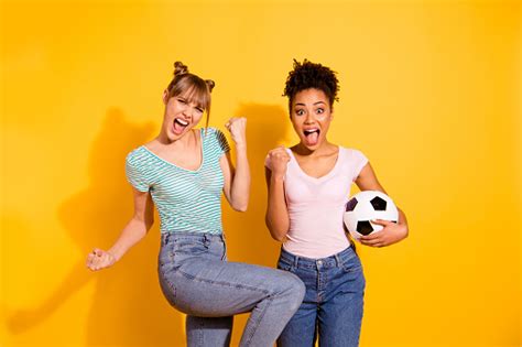 초상화 쾌활 한 학생 홀드 손 에너지 달성 아름 다운 롤빵 흥분 비명 목표 성공 스포티 행운 인상 주먹 물결 모양의 곱슬 청바지 최고 매듭 유행 스타일 세련 된 T 셔츠