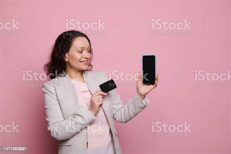 예쁜 여자 성공적인 비즈니스 여성 또는 은행 고객 미소 짓고 카메라에 검은 신용 카드와 스마트 폰을 보여줍니다 Brand Name Mobile Payment에 대한 스톡