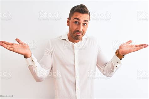 고립 된 배경에 우아한 셔츠를 입고 젊은 잘 생긴 사업가는 팔과 손을 들고 단서와 혼란스러운 표정을 짓고 있습니다 의심 개념 사람들에 대한 스톡 사진 및 기타 이미지
