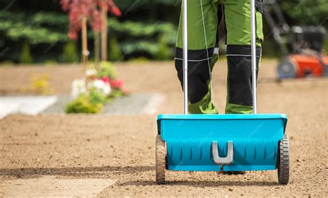 Premium Photo Gardener Seeding Grass Using Rolling Seeding Spreader