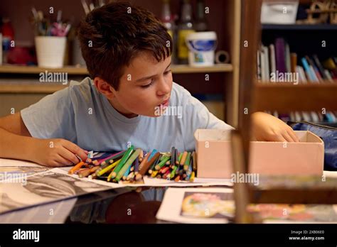 Young Boy Attentively Drawing At An Art Class Table Filled With Colored