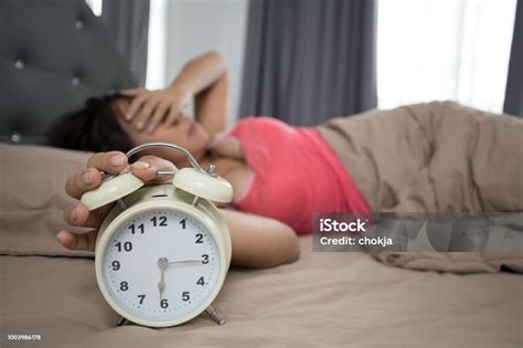 젊은 여자 소리 머리 및 불쾌 한 얼굴을 만들기와 귀에서에서 고통을 침대에 누워 일찍 일어나 충분 한 수 면을 못하고 여자 기분이 초조 그들은 알람 시계를 듣고 개념에 대한