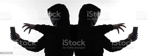 해커 익명과 손에 스마트 폰과 얼굴 마스크 검은 후드 셔츠를 입은 남자가 흰색 배경에 휴대폰을 들고 사용하고 있다 사이버 범죄 데이터 해킹 또는 개인 데이터 개념 도용 표현