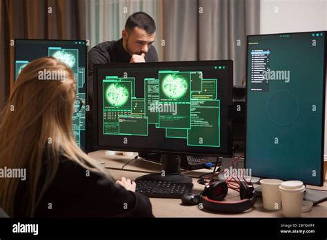 Back View Of Female Hacker Typing Virus On Computer Male Hacker In The Background Stock Photo