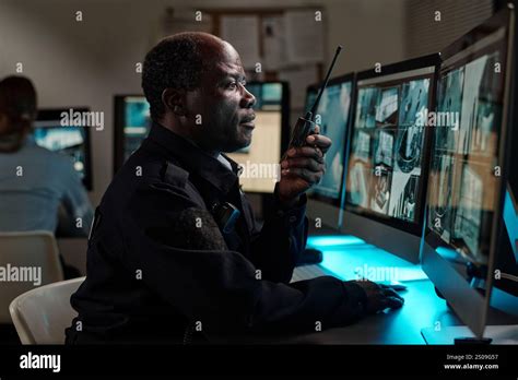 Mature African American Male Officer Sitting In Front Of Computer Monitor And Looking At Screen