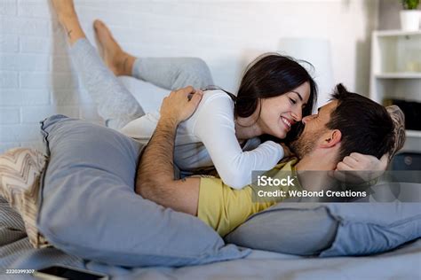 Young Couple Cuddling In Bed Enjoying Intimate Moments Together Stock