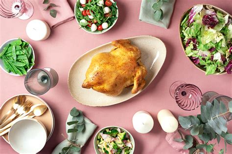 축제 가족 저녁 식사 테이블입니다 서빙 접시 샐러드와 야채 요리와 그릇 간식 전체 구운 닭고기 분홍색 초라한 배경에 유칼립투스 꽃 발렌타인 데이 여성의 날 어머니의 날