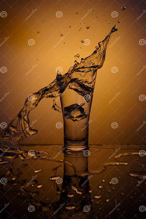 Exploding Glass Cup With Water Shattering Over Orange Background Stock