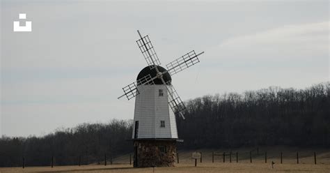 낮에는 흰 하늘 아래 갈색 잔디밭에 흰색과 갈색 풍차가 있습니다 사진 Unsplash의 무료 건물 이미지