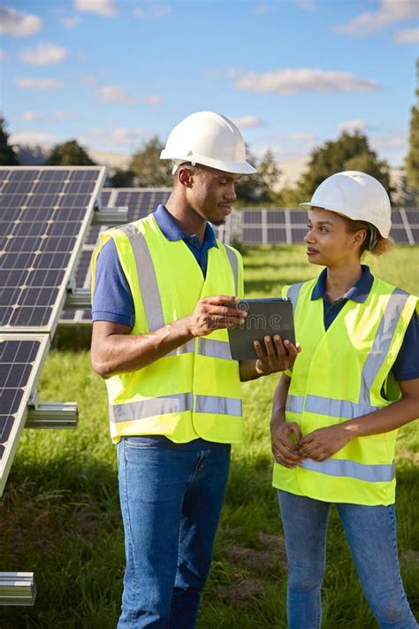 Male And Female Engineers With Digital Tablet Inspecting Solar Panels