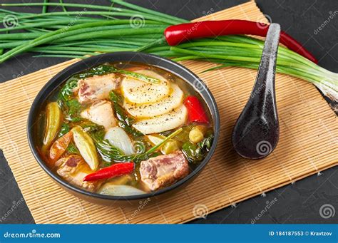 Sinigang Na Baboy Dish Or Filipino Pork Meat Soup In Black Bowl On Dark