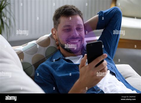 Man Using Smartphone With Facial Recognition System At Home Security Application Scanning His