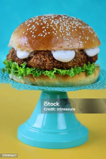 홈메이드 치킨 버거 참깨를 곁들인 빵빵 녹은 치즈와 양상추 분할 노란색과 청록색 푸른 배경이 들어 있는 청록색 케이크 스탠드의 클로즈업 이미지 전경에 초점을 맞추고 0명에