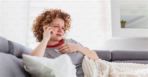 젊은 여자는 전화로 나쁜 소식을 듣는다 불행한 여자가 휴대폰으로 아래를 내려다보고 있다 우는 우울한 소녀는 소파에 앉아 전화를 들고 절망적 헤어지고 위협 모바일