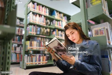 도서관 바닥에 앉아 있는 아시아 여학생 책장에서 교과서 를 열고 배우기 국제 학생에 대한 스톡 사진 및 기타 이미지 국제 학생 도서관 십대 Istock