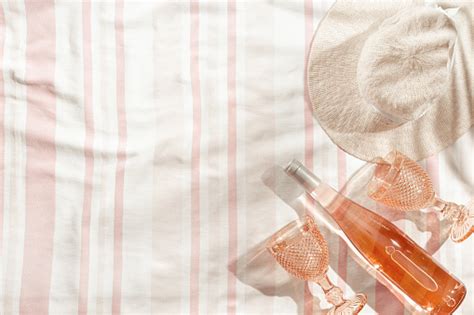 여름 라이프스타일 플랫은 두 개의 컬러 와인 잔 병 장미 와인 줄무늬 비치 타월에 태양 모자를 배경으로 누워 있습니다 여름 해변 개념 휴가 및 파티 로맨스 피크닉 탑 뷰