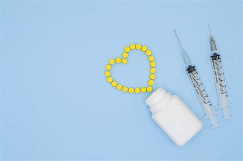 밝은 파란색 배경에 주사기로 병에서 쏟아져 나오는 심장 모양의 알약 복사 공간이 있는 위쪽 보기입니다 의료 및 건강 관리 개념 0명에 대한 스톡 사진 및 기타 이미지