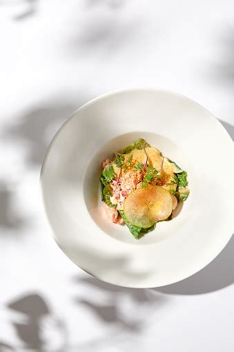 거친 그림자가있는 흰색 테이블에 게 고기 에스푸마 소스 및 양상추를 곁들인 우아한 샐러드 여름 메뉴에 게와 크림 소스를 곁들인 그린 샐러드 미적 음식 해산물 전채 갈고리