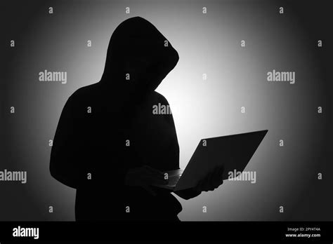 Mysterious Man Wearing Black Hoodie Using Laptop In The Dark Room Hacker And Cyber Security
