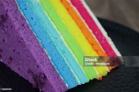 검은 딤플 트레이에 버터 아이싱 크림과 멀티 컬러 스폰지 층 사진을 보여주는 무지개 케이크의 조각의 이미지 레인보우 케이크에 대한 스톡 사진 및 기타 이미지 Istock