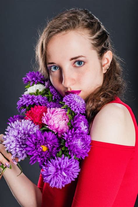 Стильный страстно красивая девушка с фиолетовыми астрами на темном фоне