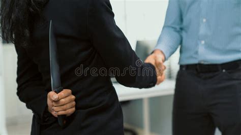 Back View Of Businesswoman Shaking Hands With A Knife Behind His Back