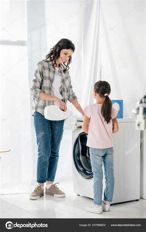 Mother Pouring Liquid Laundry Detergent Washer Wile Daughter Pink Shirt