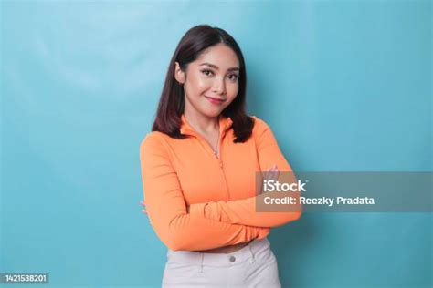 팔을 접은 채 서서 파란 배경 위에 고립된 카메라를 바라보는 자신감 넘치는 웃는 소녀의 초상화 자신감에 대한 스톡 사진 및 기타 이미지 Istock