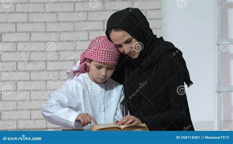 Happy Arabic Mother And Son Together Sitting On The Couch And Reading A