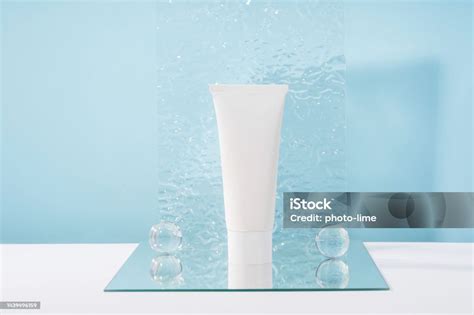파란색 배경에 브랜드 없는 화장품 크림 흰색 플라스틱 튜브 모형이 세련된 소품 거울과 유리 공 아크릴 접시로 있습니다 몸과 건강 관리 아름다움 제품 포장 제품 발표 0명에