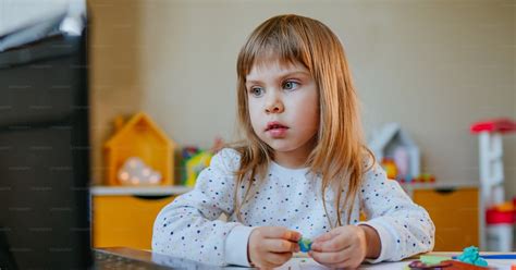 어린 소녀는 실내에서 노트북으로 온라인 학습 수업을 보고 다채로운 점토를 성형합니다 원격 가정 학습 개념입니다 사진 Unsplash의 사진술 이미지