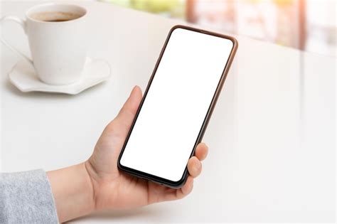 모형 전화 커피숍에서 빈 화면이 있는 휴대폰 스마트폰을 들고 있는 손을 닫습니다 프리미엄 사진