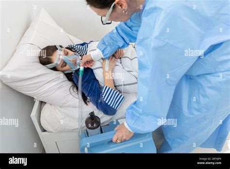 The Doctor Controls The Connection Of The Ventilator The Teenager Lies On A Hospital Bed
