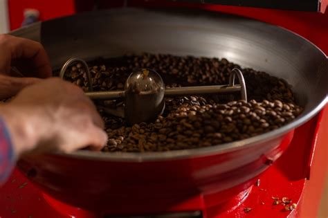 곡물 냉각기가 있는 현대적인 장비에 있는 향기로운 커피 콩 산업 개념입니다 콩을 굽는 데 사용되는 현대적인 기계 냉각 실린더에 커피 로스터를 붓고 있습니다 프리미엄 사진