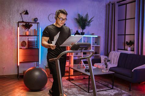 회색 스포츠웨어와 헤드셋 교육을 받는 활동적인 아시아 사업가가 집에서 종이로 작업합니다 35 39세에 대한 스톡 사진 및 기타