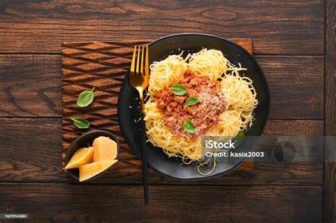 파스타 스파게티 볼로냐세 오래된 나무로 된 소박한 테이블 배경에 흰색 접시에 볼로냐 소스 토마토 소스 치즈 파르 메산 및 바질과