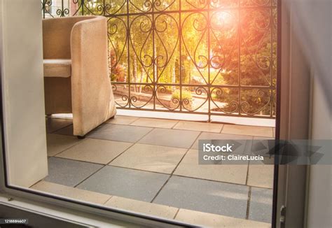 객실에서 금속 난간이 있는 테라스 또는 발코니의 전망을 감상하실 수 있습니다 태양은 일몰 동안 투명 커튼과 나무를 통해 빛난다 0명에 대한 스톡 사진 및 기타 이미지