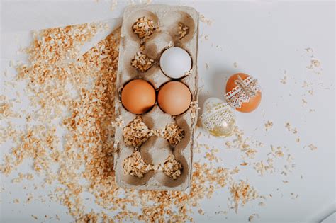 톱밥이 있는 흰색 배경에 있는 판지 상자에 부활절 달걀 레이스 테두리가 있는 부활절 달걀 레이스와 밧줄부활절 달걀을 장식하는 과정 반짝이 황금 부활절 달걀 0명에 대한 스톡