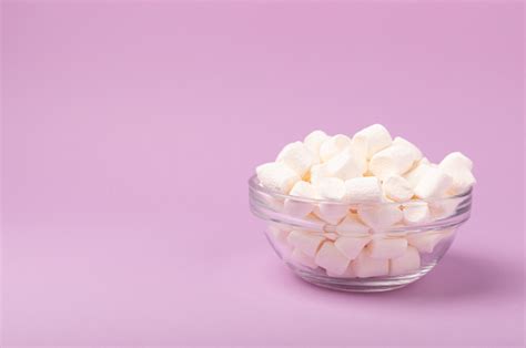 유리 그릇에 라일락 배경에 마시멜로 하얀 마시멜로 플랫 레이 간식을위한 과자와 스낵 씹는 사탕 클로즈업 공간을 복사합니다 텍스트를위한 장소 겨울 음식 개념 개체 그룹에 대한