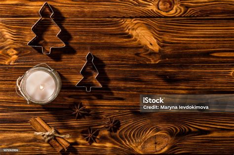 닫기 최대 플랫이 하다 화이트 유리 촛대에 촛불 점화 향신료와 크리스마스 나무의 형태로 금속 금형 주위에 누워 있습니다 소박한 갈색 나무 배경입니다 0명에 대한 스톡 사진