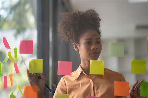아프리카 계 미국인 사업가들은 유리 벽에 포스트잇을 사용하여 개발하고 성공으로 성장시키기위한 전략적 사업 계획을 작성합니다 20
