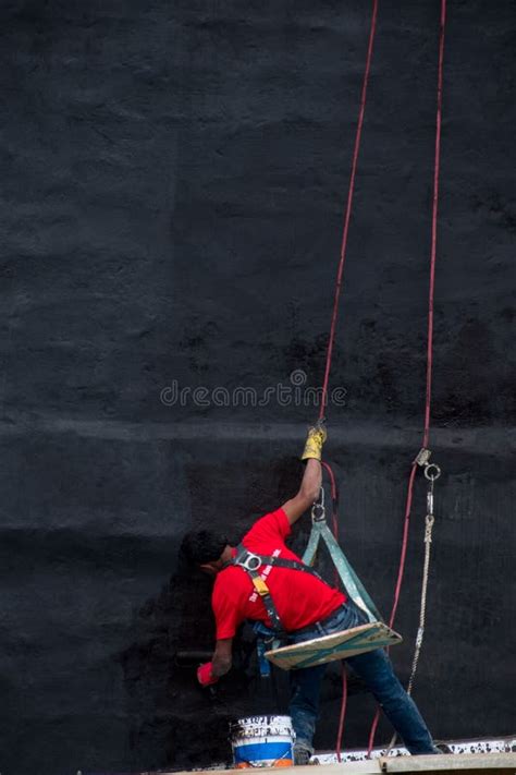 Man Standing On A Wooden Suspended Scaffold And Painting A Wall In Black Stock Photo Image Of