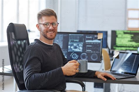 Portrait Of Software Programmer Smiling At Camera While Posing At Workplace In Office With